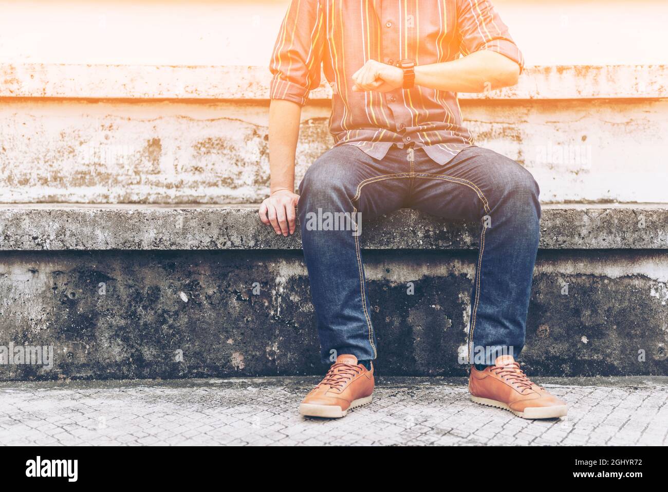 Blurry Man look at times and sitting on outdoor grandstand. Cross ...