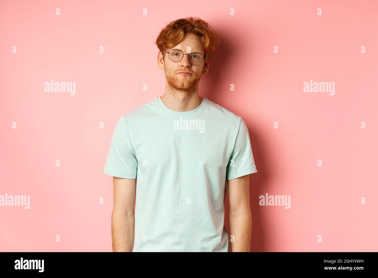 Sad and gloomy redhead bearded man in t-shirt and glasses, staring at ...