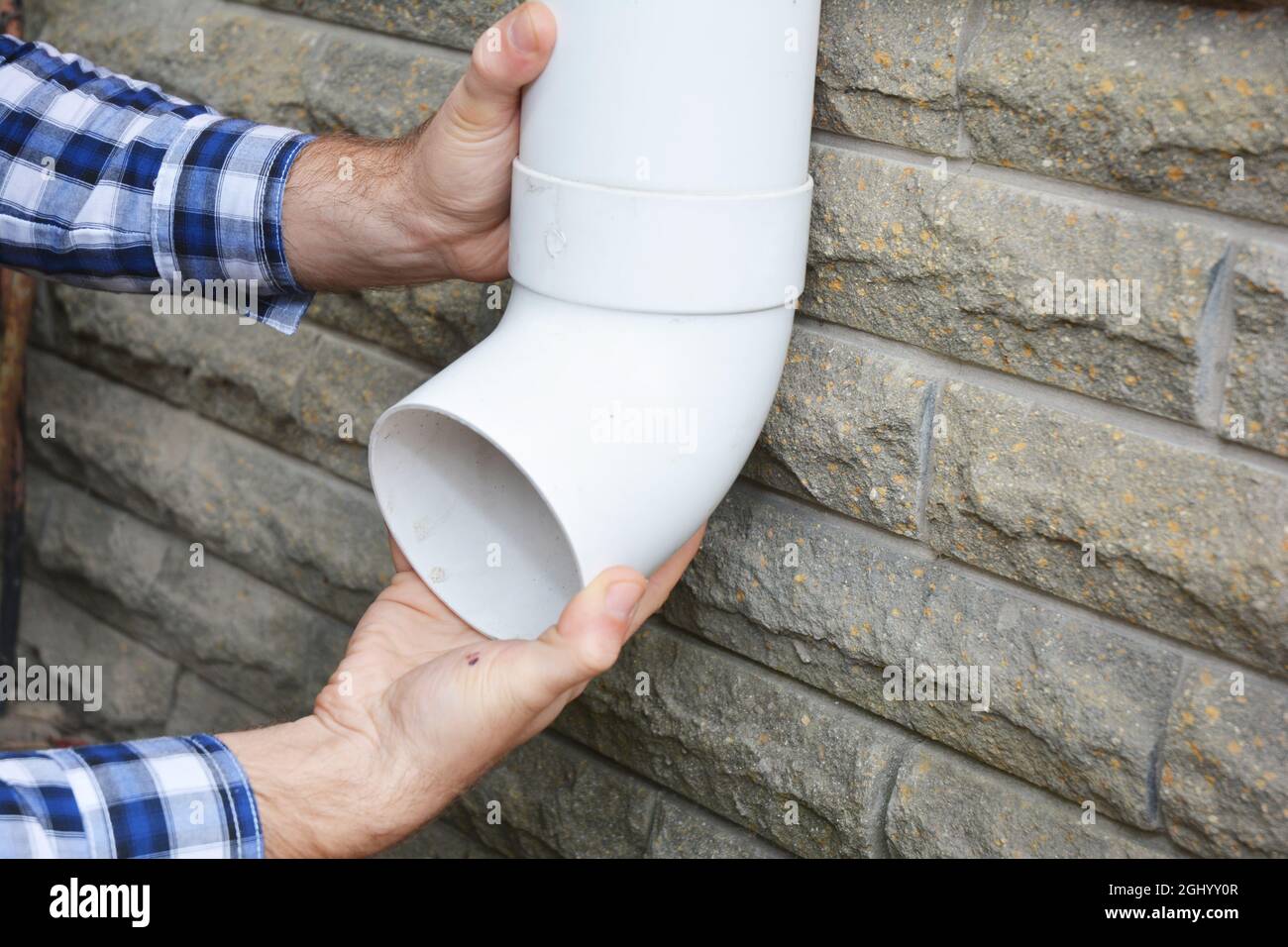 A building contractor is installing new rain gutter system attaching ...