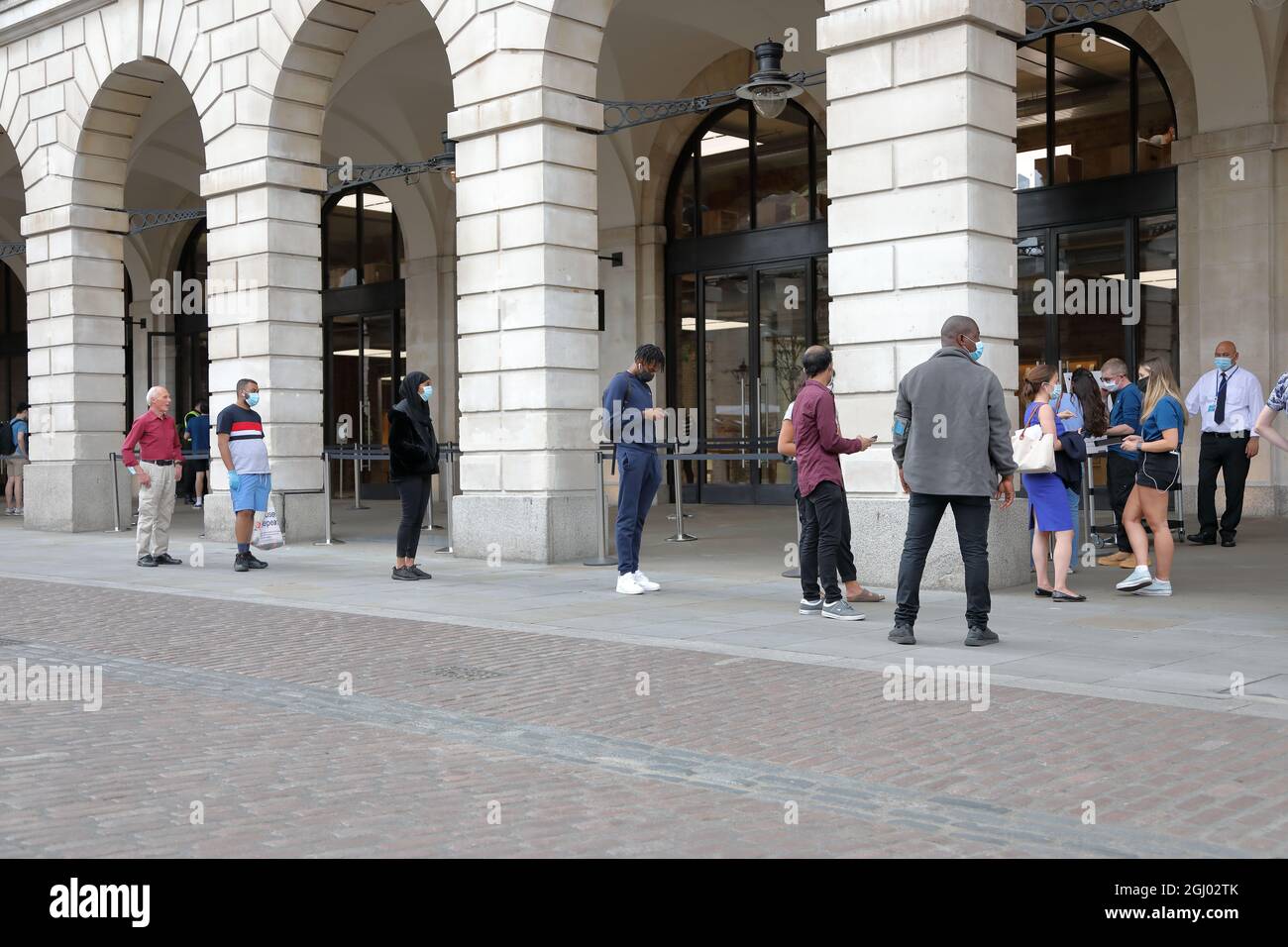 Social distancing in queue by customers wearing facemask Stock Photo ...