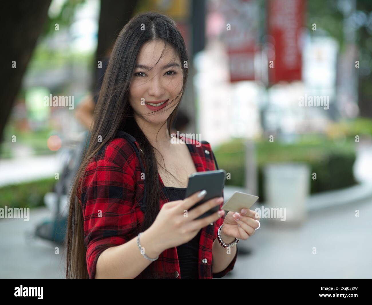 Attractive beautiful millennial woman with smartphone and credit card ...
