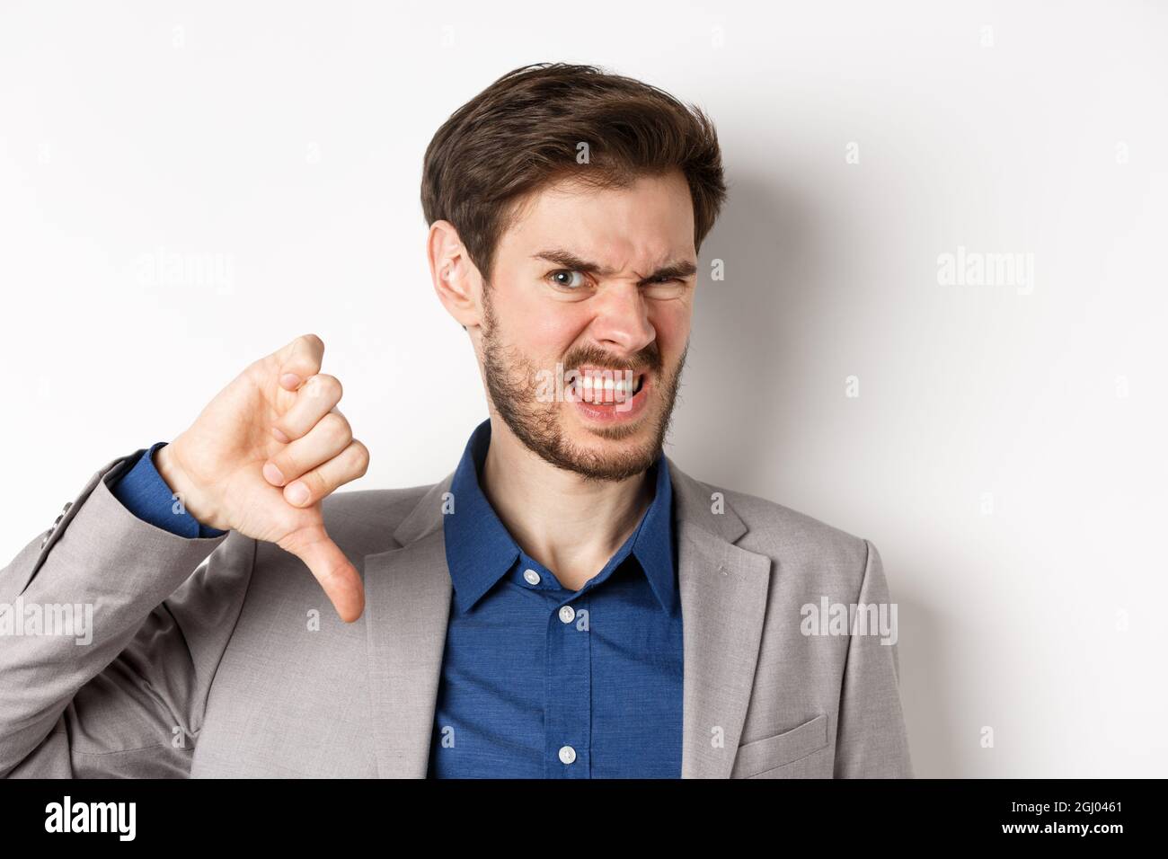Close-up of disgusted guy in suit grimacing upset, showing thumbs down ...
