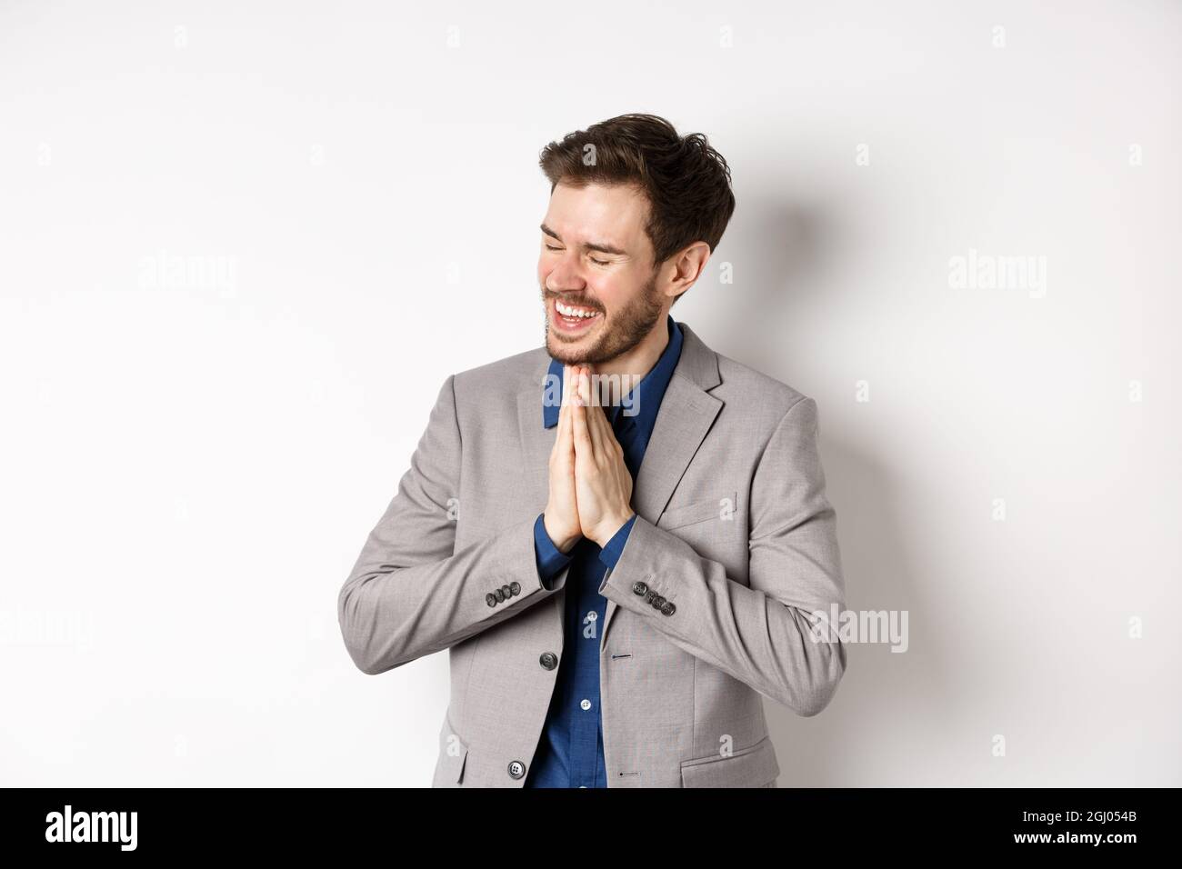 Happy and thankful businessman rejoicing, holding hands in begging or ...