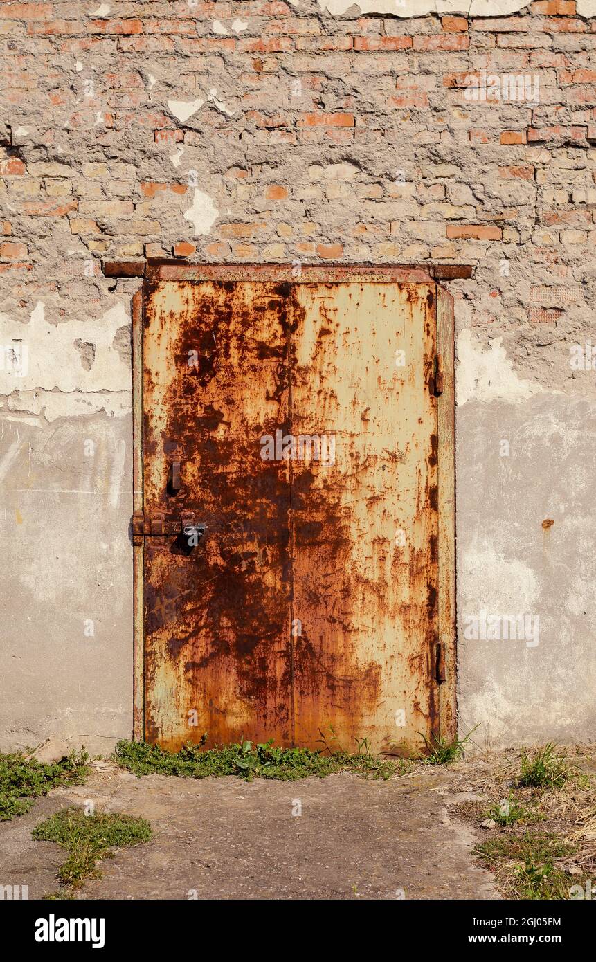 An old rusty metal door in a stone wall. The front door is locke Stock ...
