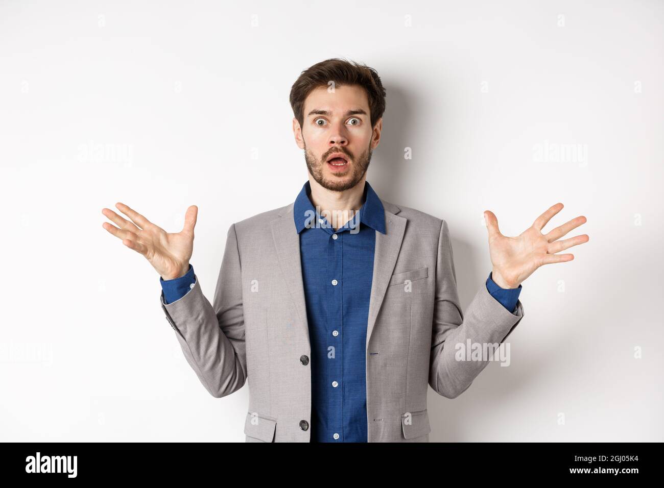 Shocked bearded guy in jacket spread hands sideways, gasping and ...