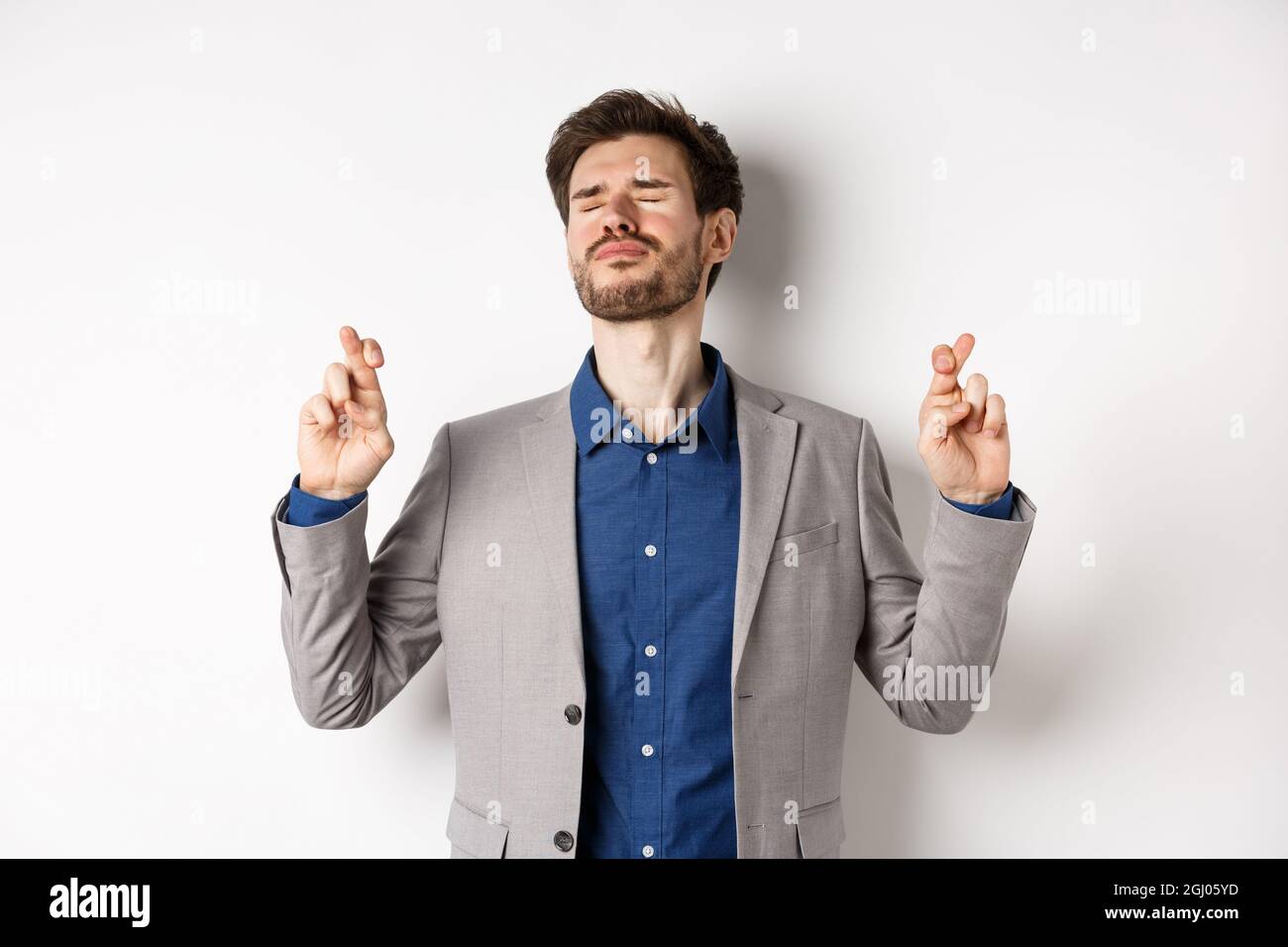 Nervous businessman in suit begging god, holding fingers crossed with ...