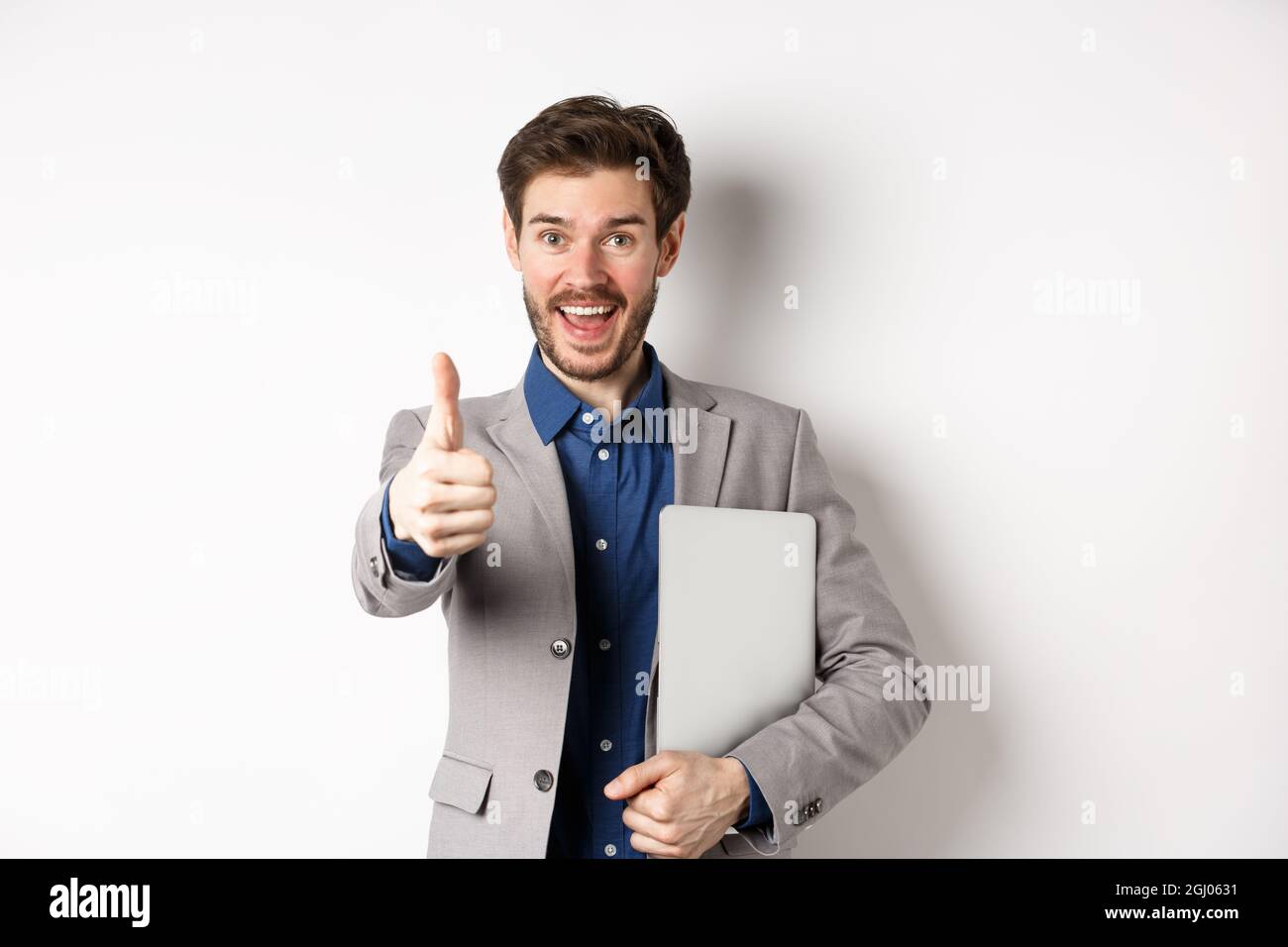 Good job. Happy smiling business man in suit holding laptop, showing ...