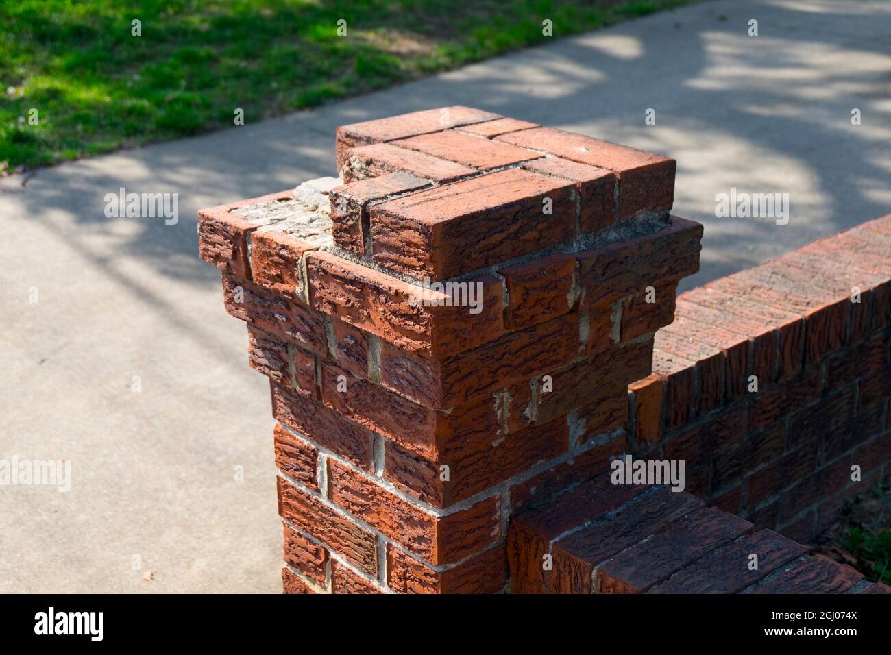 A corner column of a brick wall surrounding a house, missing a few ...