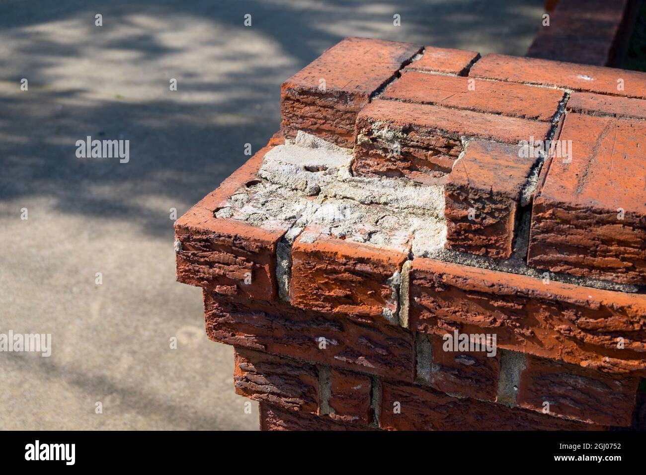 A corner column of a brick wall surrounding a house, missing a few ...