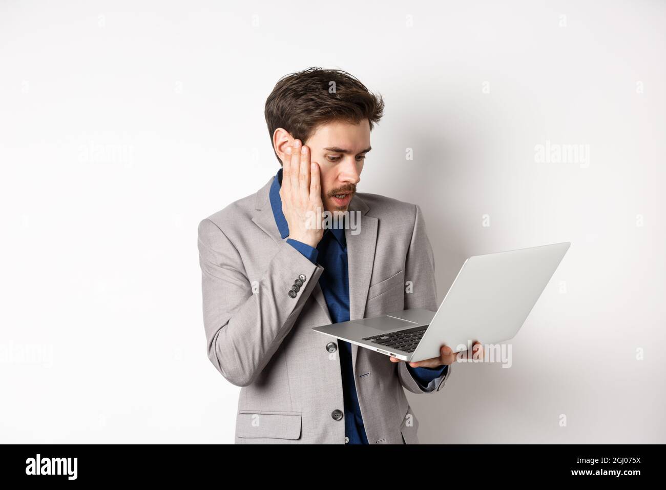 Shocked and worried businessman making mistake on laptop, looking at ...