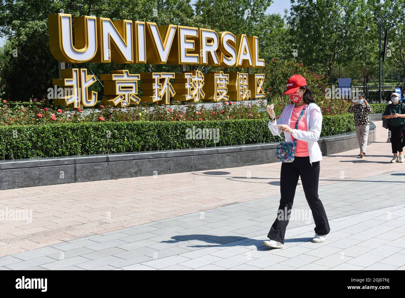 Tourists wearing face masks walk past the Chinese and English signs of ...