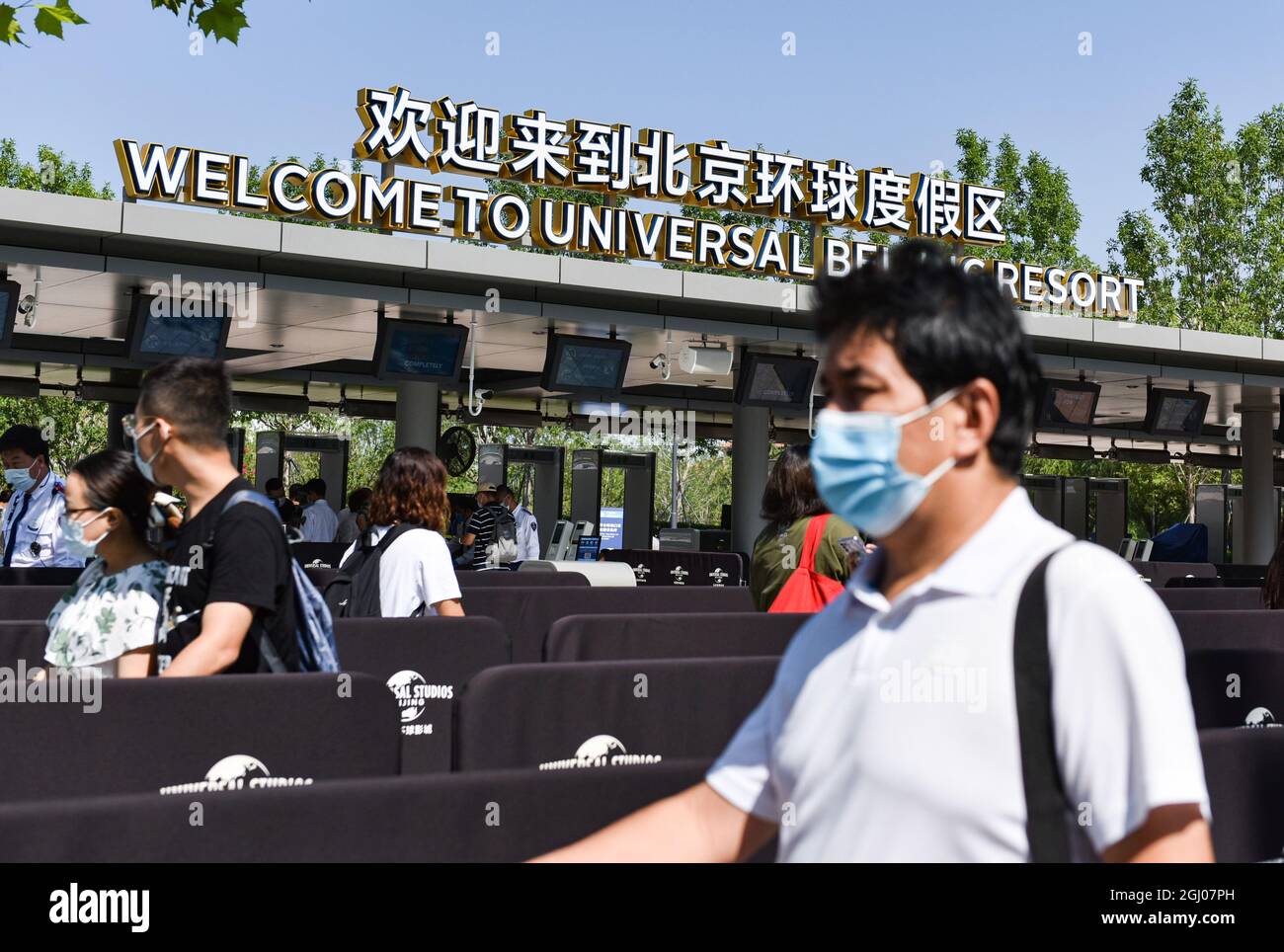 Tourists wearing face masks walk past the Chinese and English signs of ...