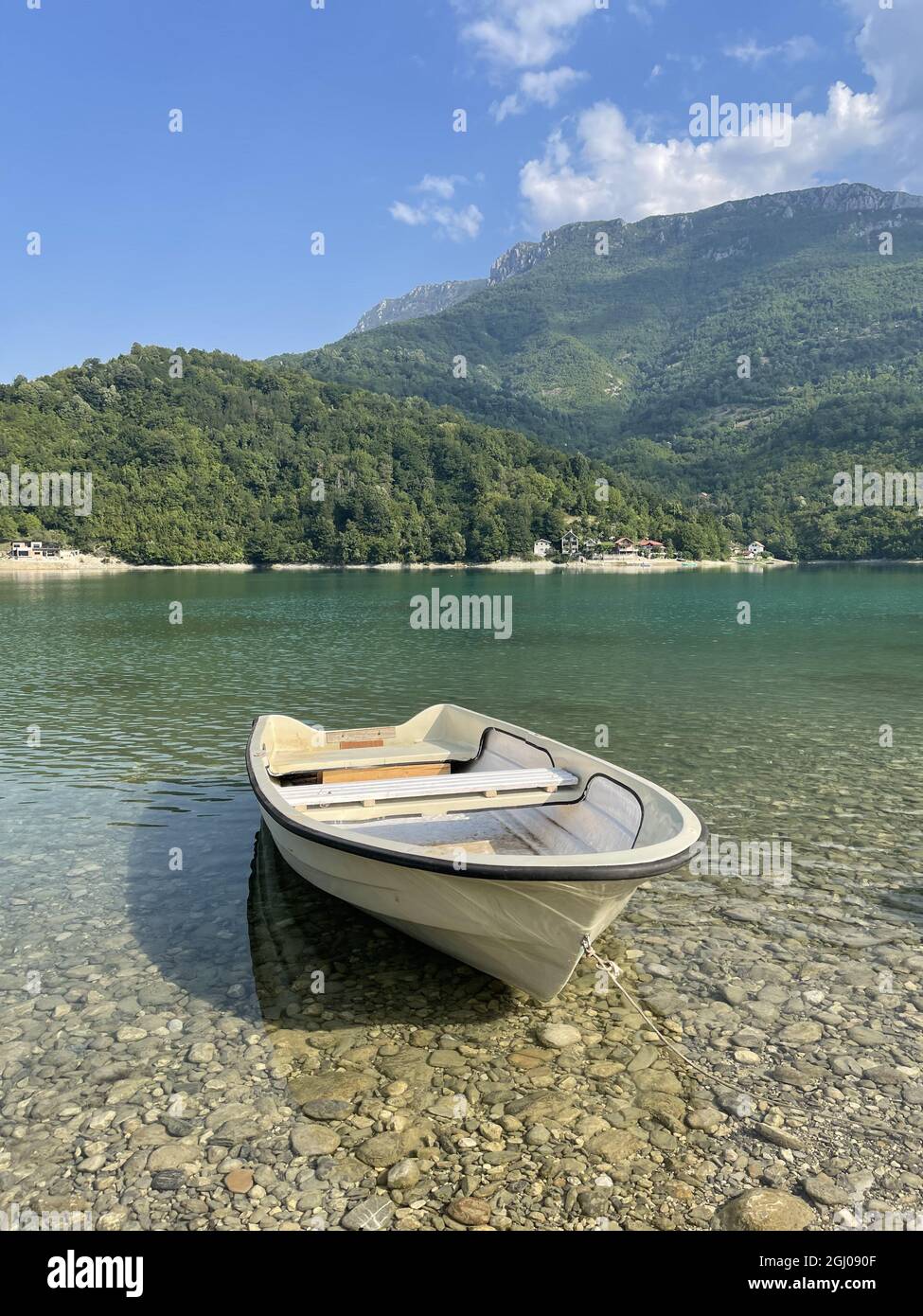 Vertical shot of a small white boat in a crystal water and a natural ...