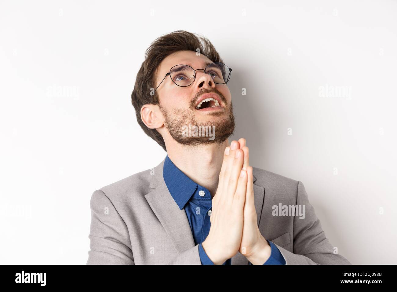 Close-up of handsome bearded man in glasses and suit looking up and ...