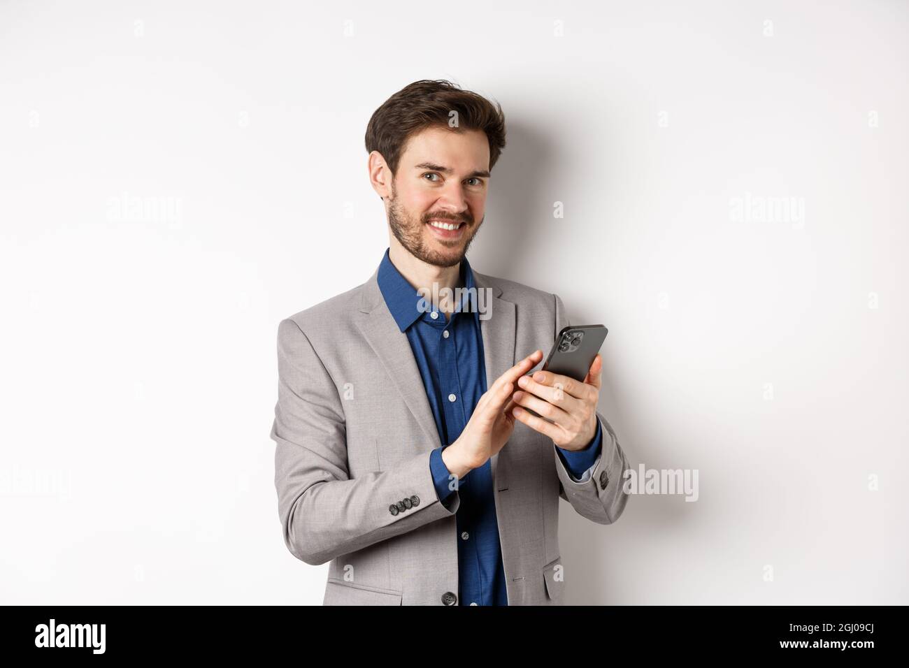 Smiling successful business man using smartphone on white background ...
