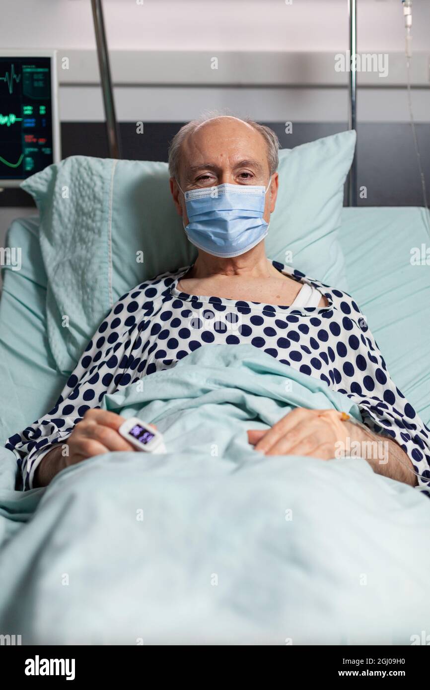 Portrait of sick senior man patient with chirurgical mask resting in ...