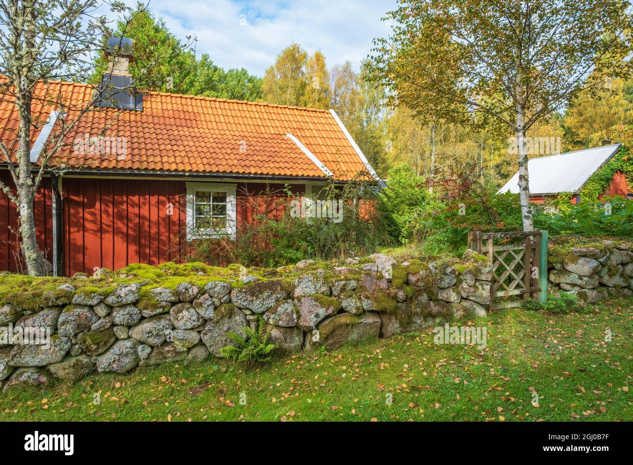 Idyllic red cottage with a stone wall and a gate Stock Photo - Alamy