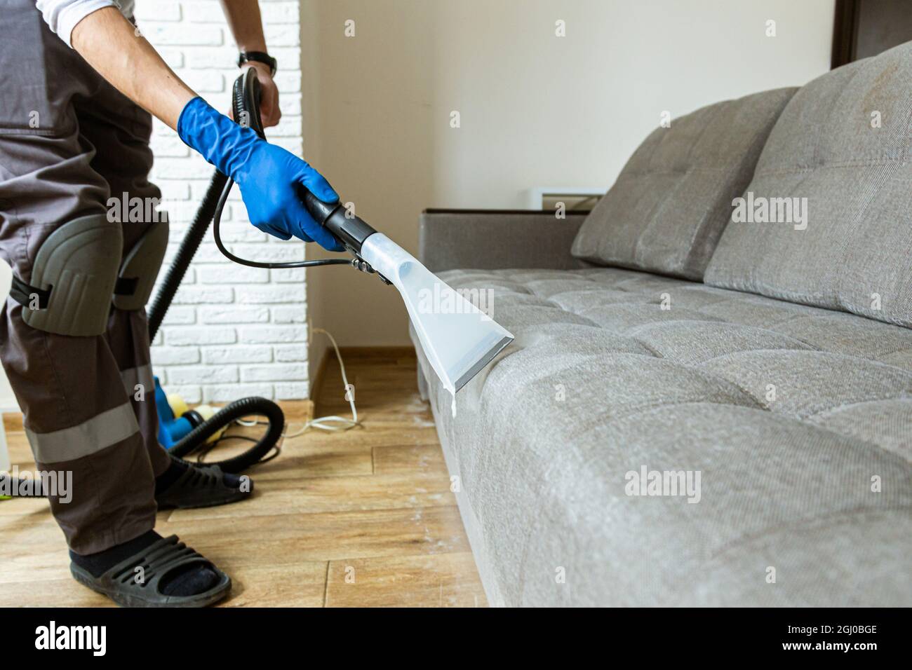 Close up man hand in protective rubber glove cleaning sofa with ...