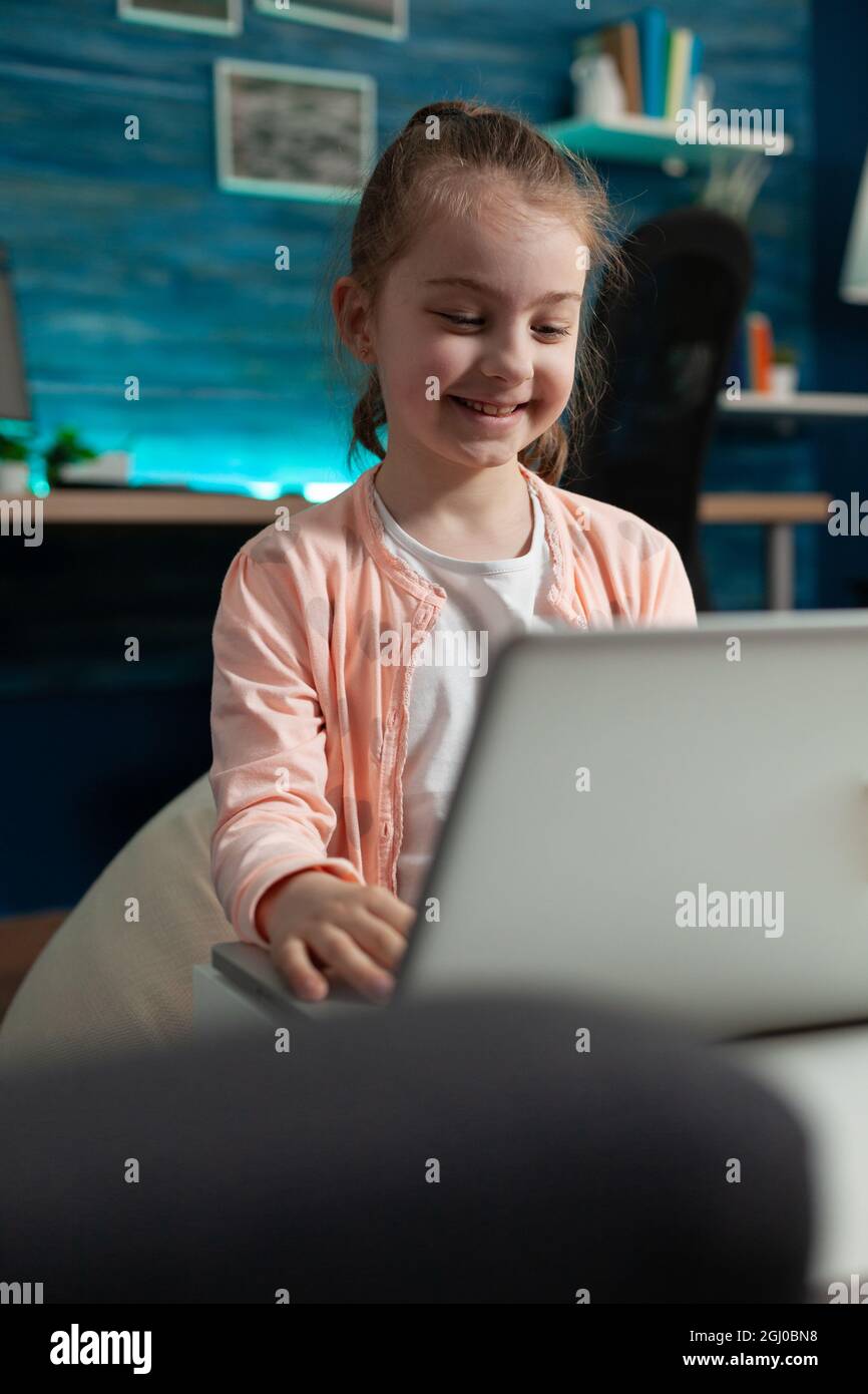 Smart little child typing on modern laptop at home desk using internet ...