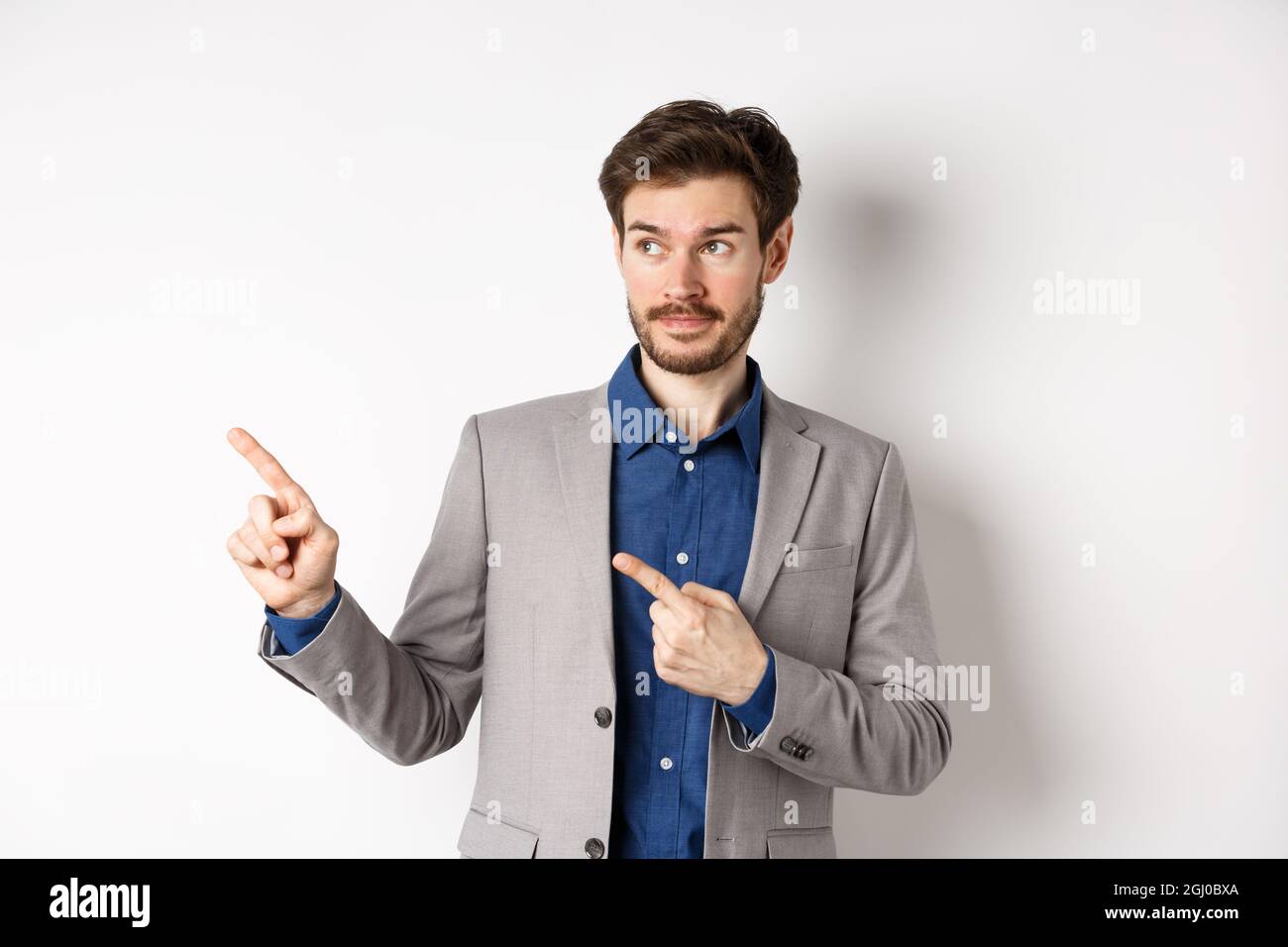 Doubtful male entrepreneur in suit looking and pointing left with ...