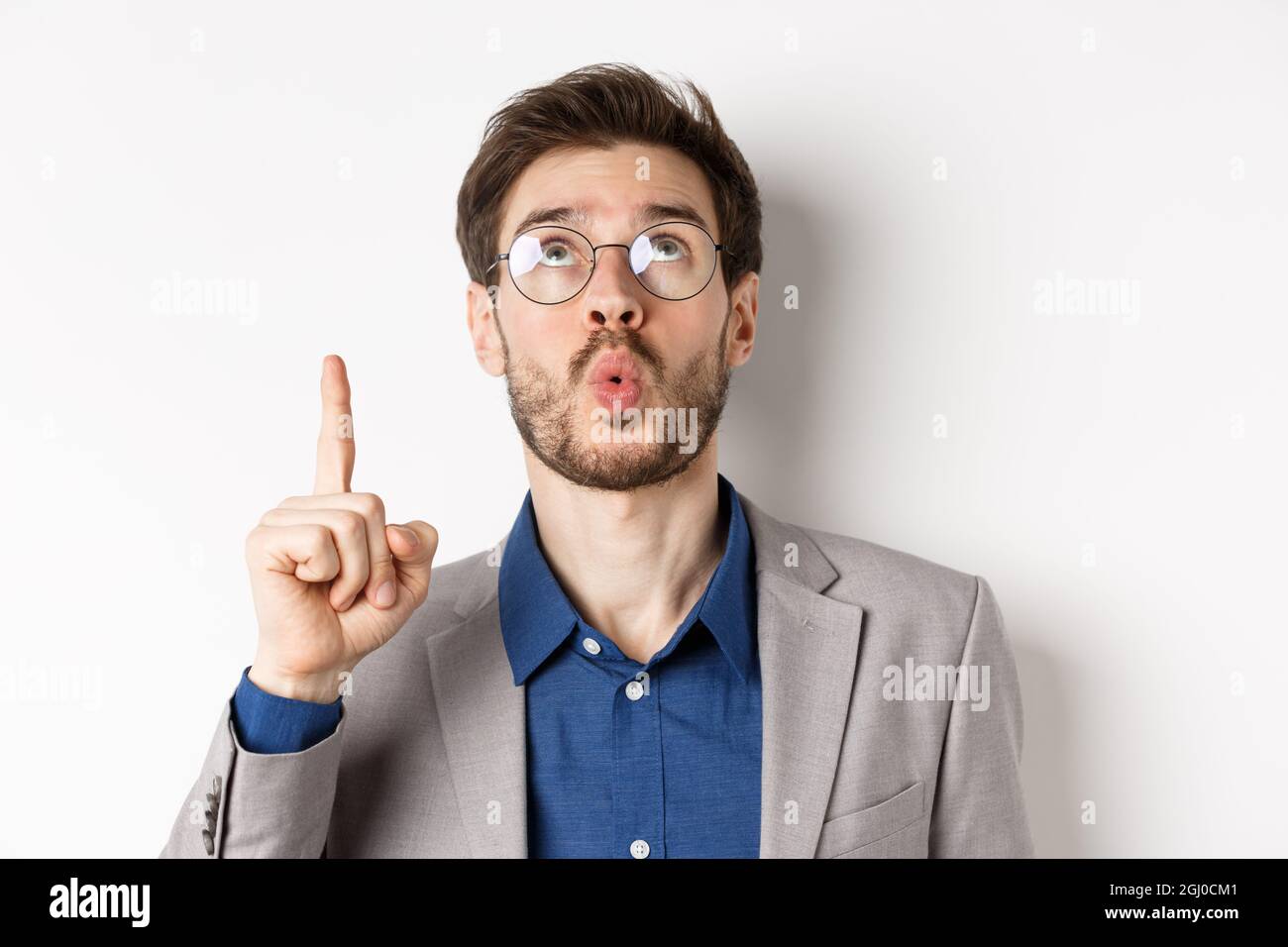 Excited handsome man in glasses and business suit, look up and pointing ...