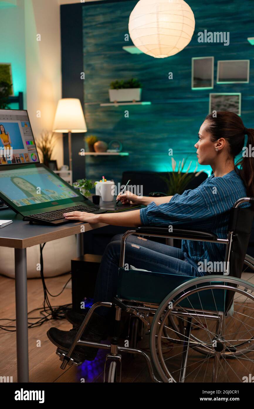 Disabled woman photographer in wheelchair working on picture editing ...