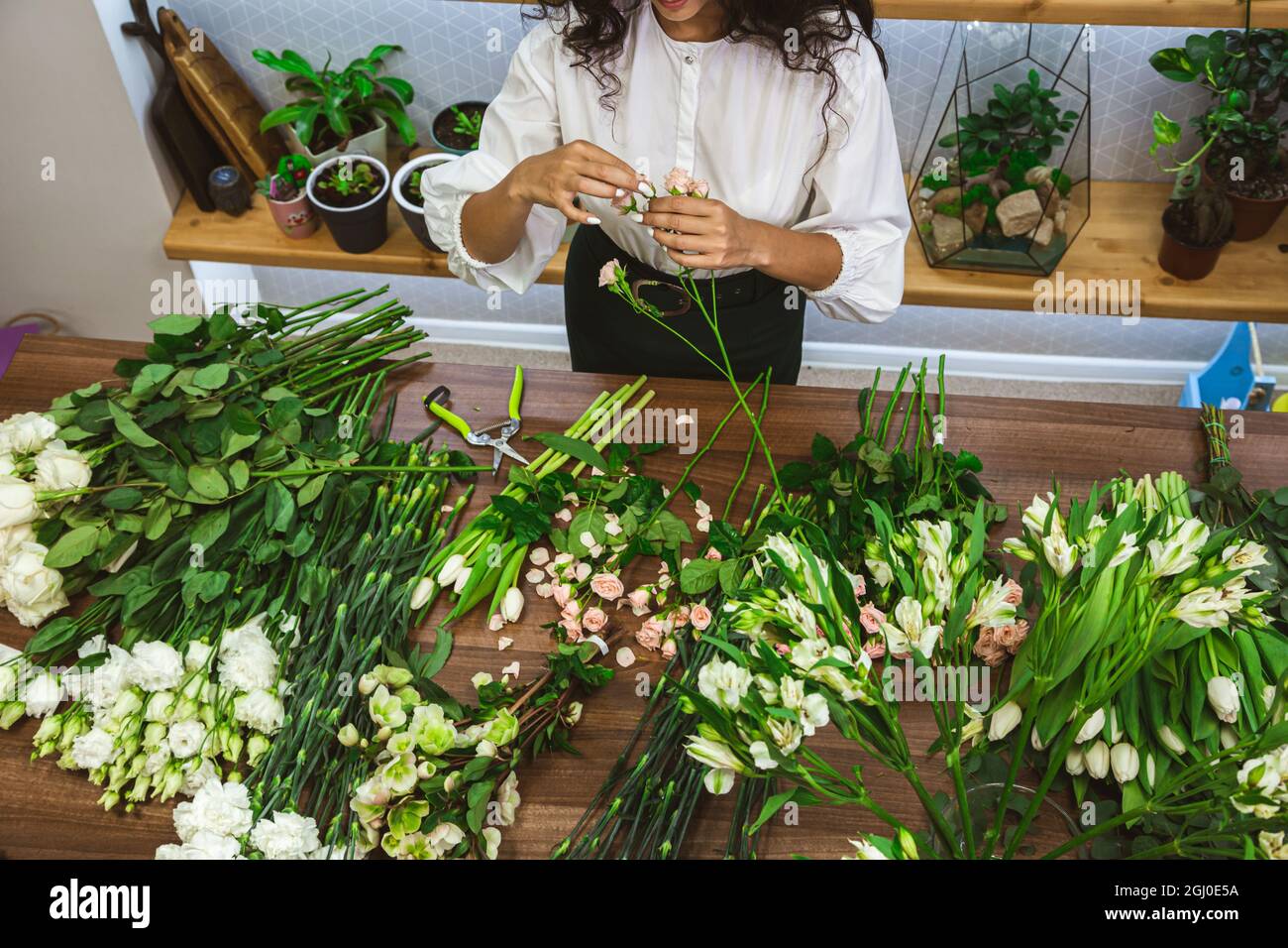 Attractive young woman florist is working in a flower shop Stock Photo ...