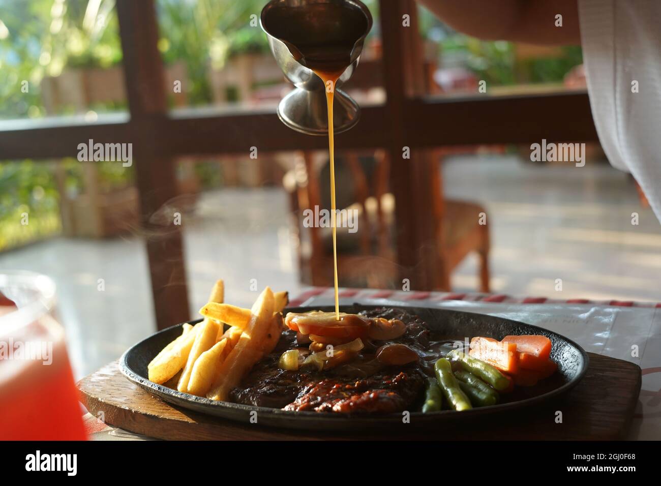 Hand pouring sauce on the dish with meat and vegetables Stock Photo - Alamy