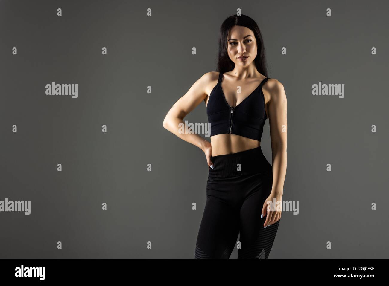 Tough young woman standing on grey background. Muscular female looking ...