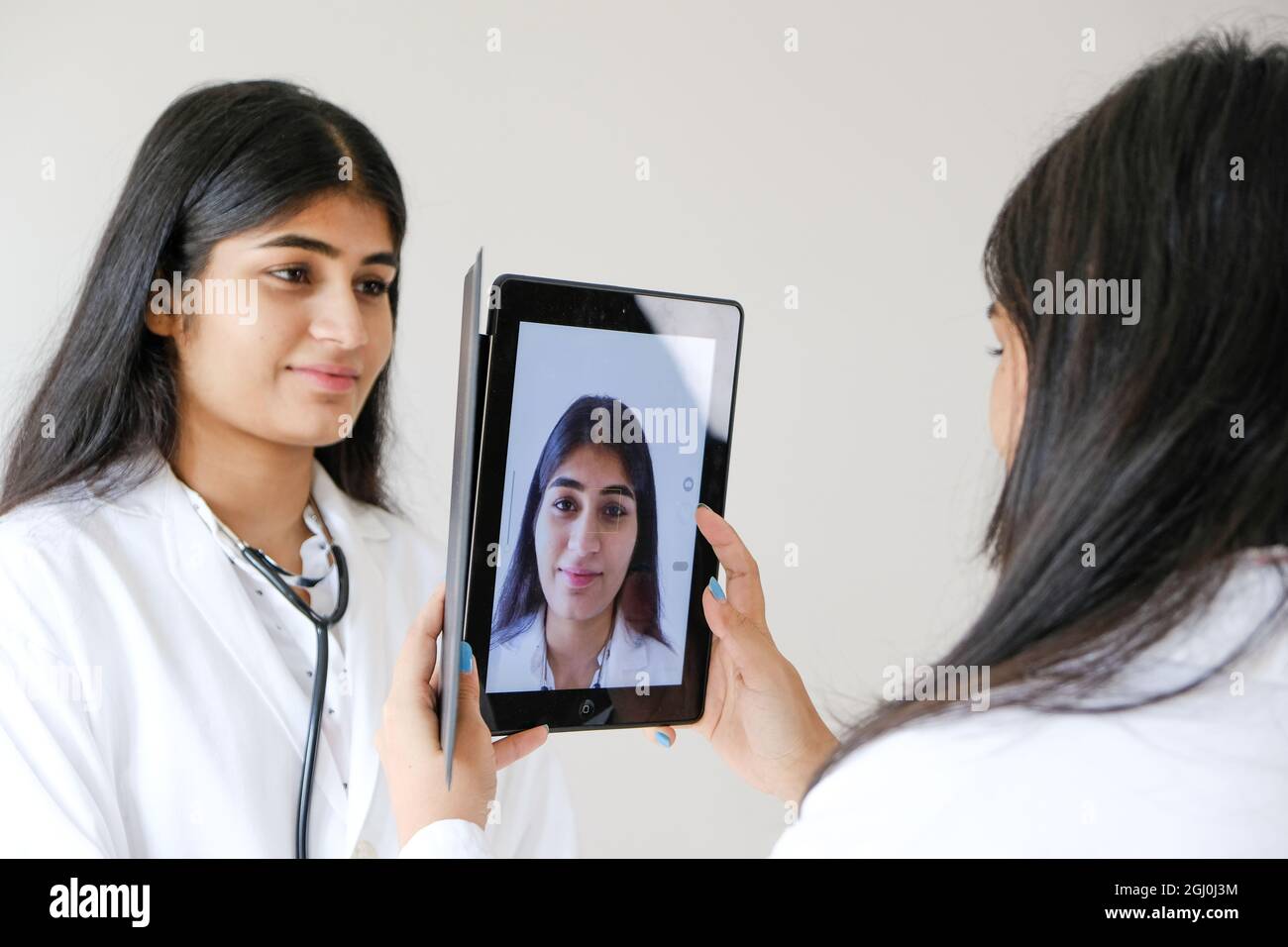Female taking a picture of another young female doctor with a tablet ...