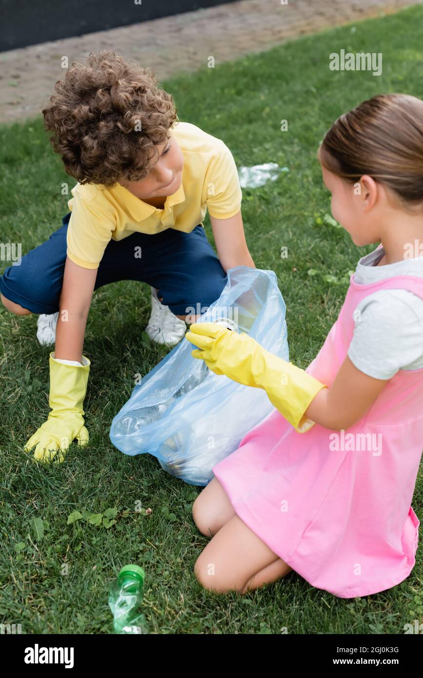 Kids in rubber gloves putting trash in bag on grass Stock Photo - Alamy