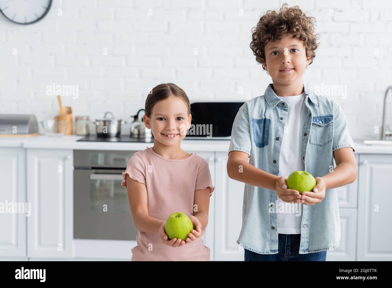 Positive brother and sister holding apples in kitchen Stock Photo - Alamy
