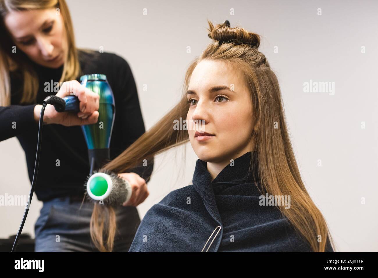 Master woman hairdresser dries the girl's hair with a hairdryer and ...
