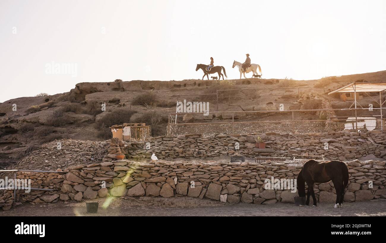 Young people riding horses doing excursion at farm ranch in sunset time ...