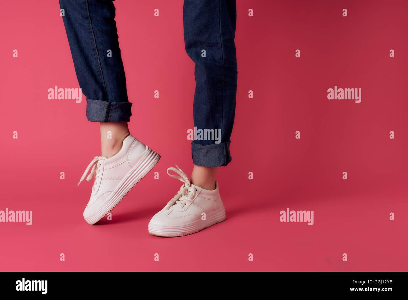 inverted female legs in white sneakers pink background cropped view ...