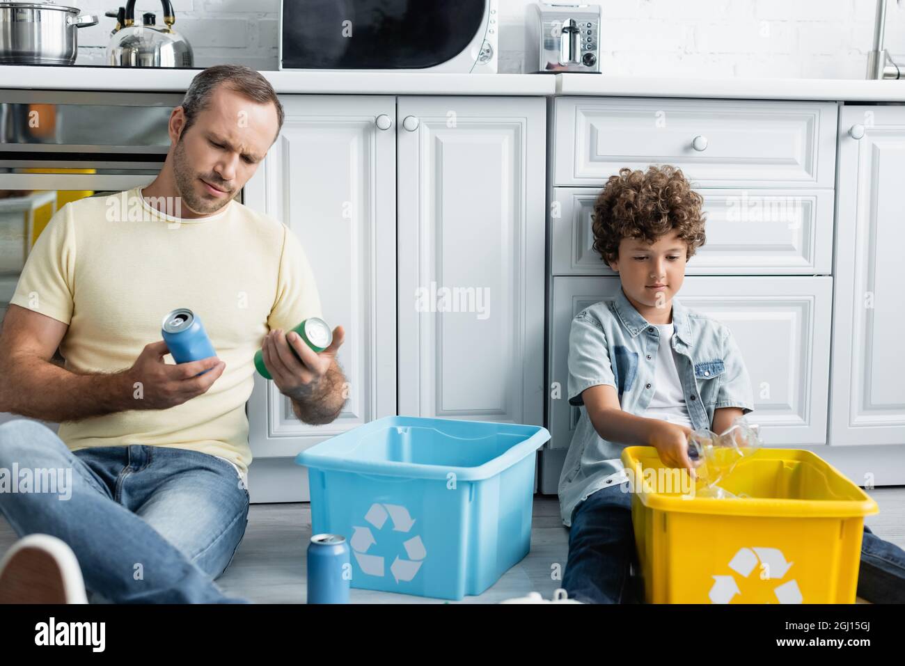 Man and son sorting trash in boxes with recycle sign in kitchen Stock ...