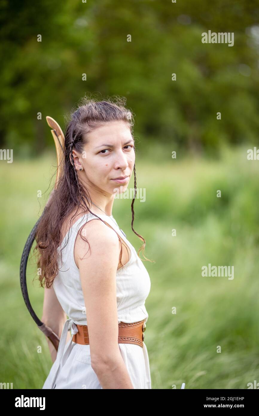 A Hungarian woman in a linen dress standing with a bow on the field ...