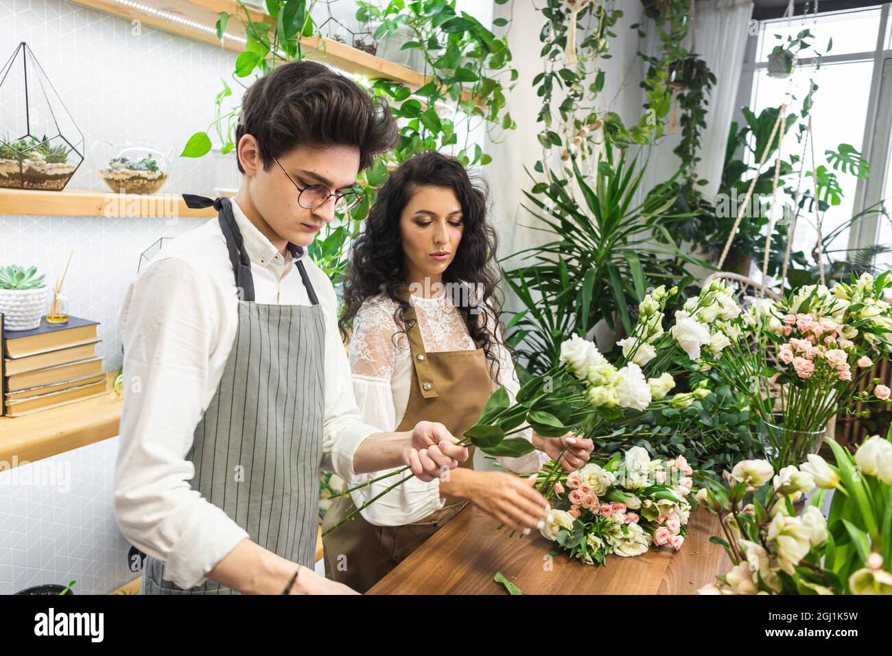 Attractive experienced female florist teaches a young man how to work ...
