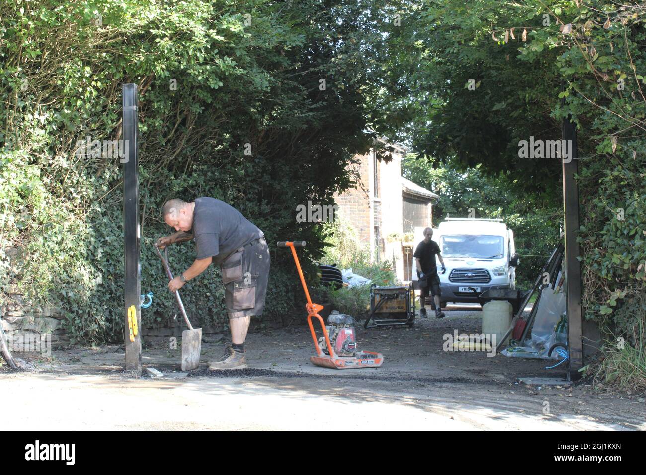 Caucasian workman levelling tarmac where a channel was cut for ...