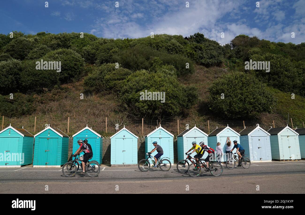 People cycle past beach huts on Bournemouth Beach in Dorset. Picture ...