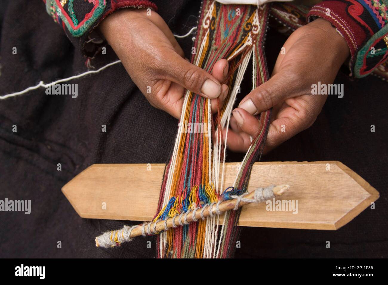 Woman in traditional dress weaving using a backstrap loom (close-up of ...