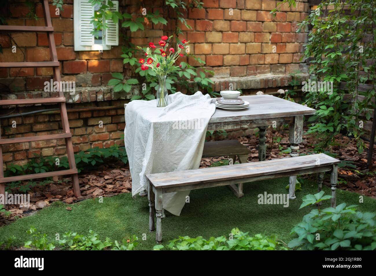 Outside Terrace with brick wall and plants, dining table and wooden ...