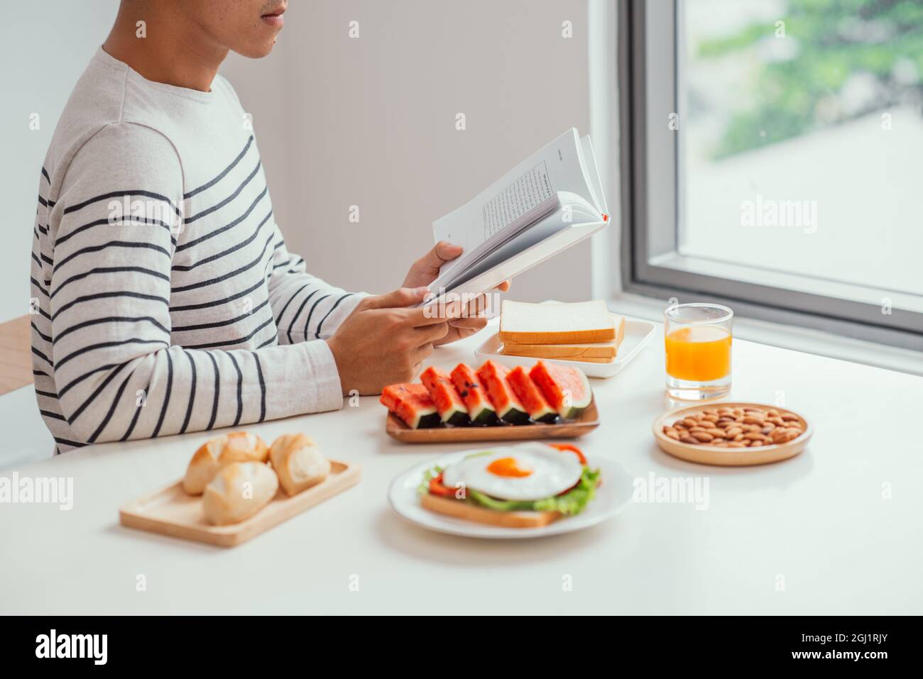 man eating breakfast and reading book at home Stock Photo - Alamy