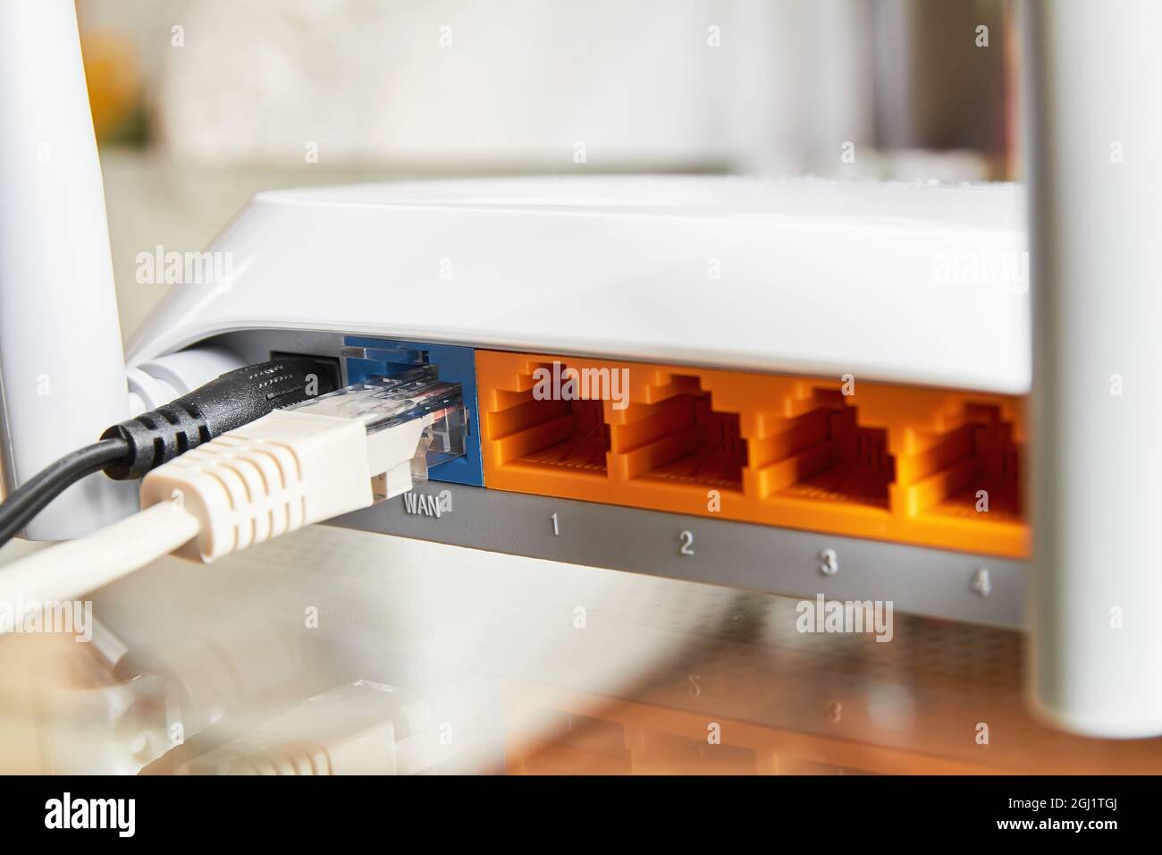 White wireless router on a glass table connected by cable to the ...