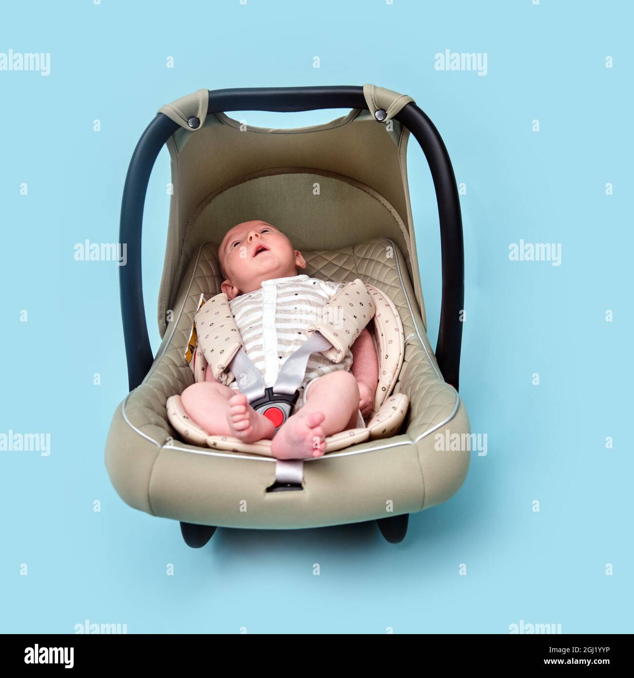 Baby in infant car seat on blue studio background. Carrier for ...