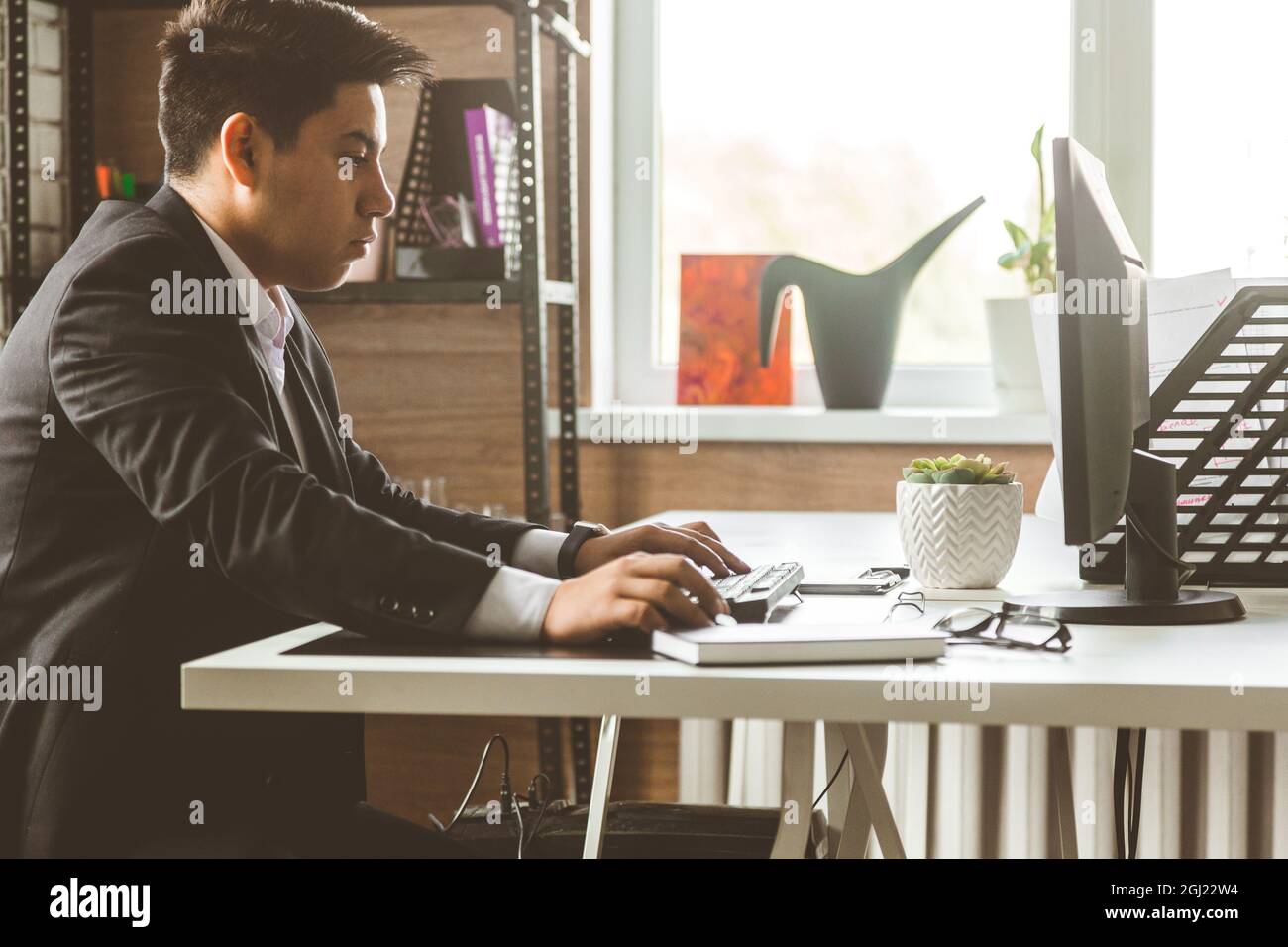 Young office worker sitting at desk, using computer. Two business man ...