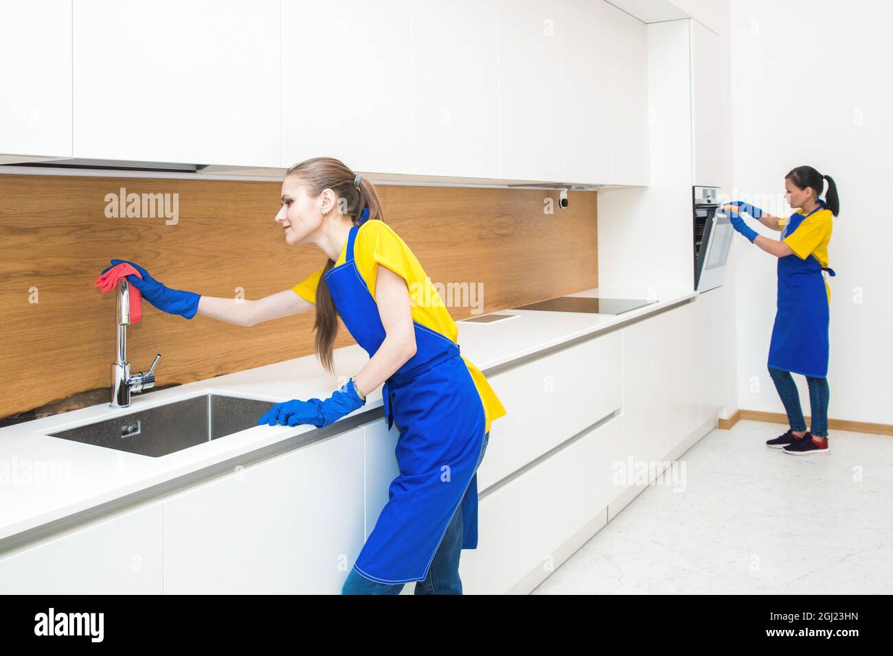 professional cleaning service. Two women in working uniform, in aprons ...