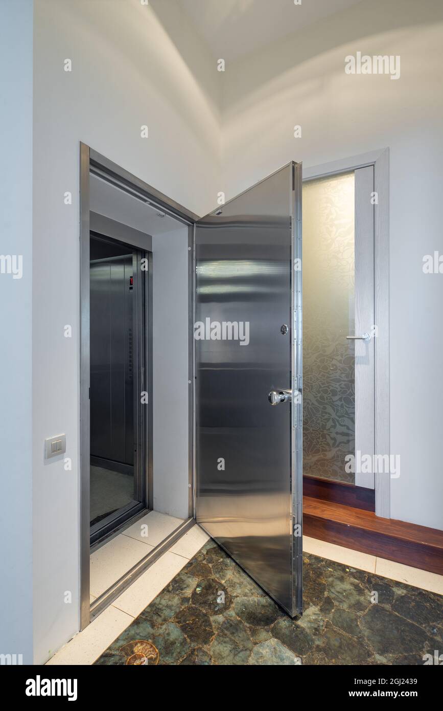Modern interior of entrance in luxury apartment. Opened iron door ...