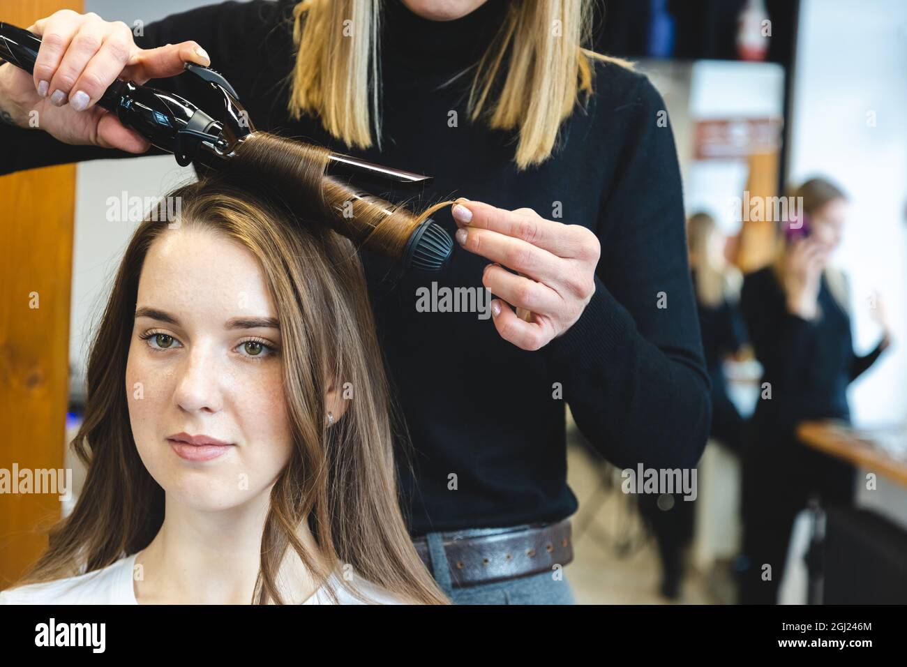 Master woman hairdresser gently curls hair curling girl in a beauty ...