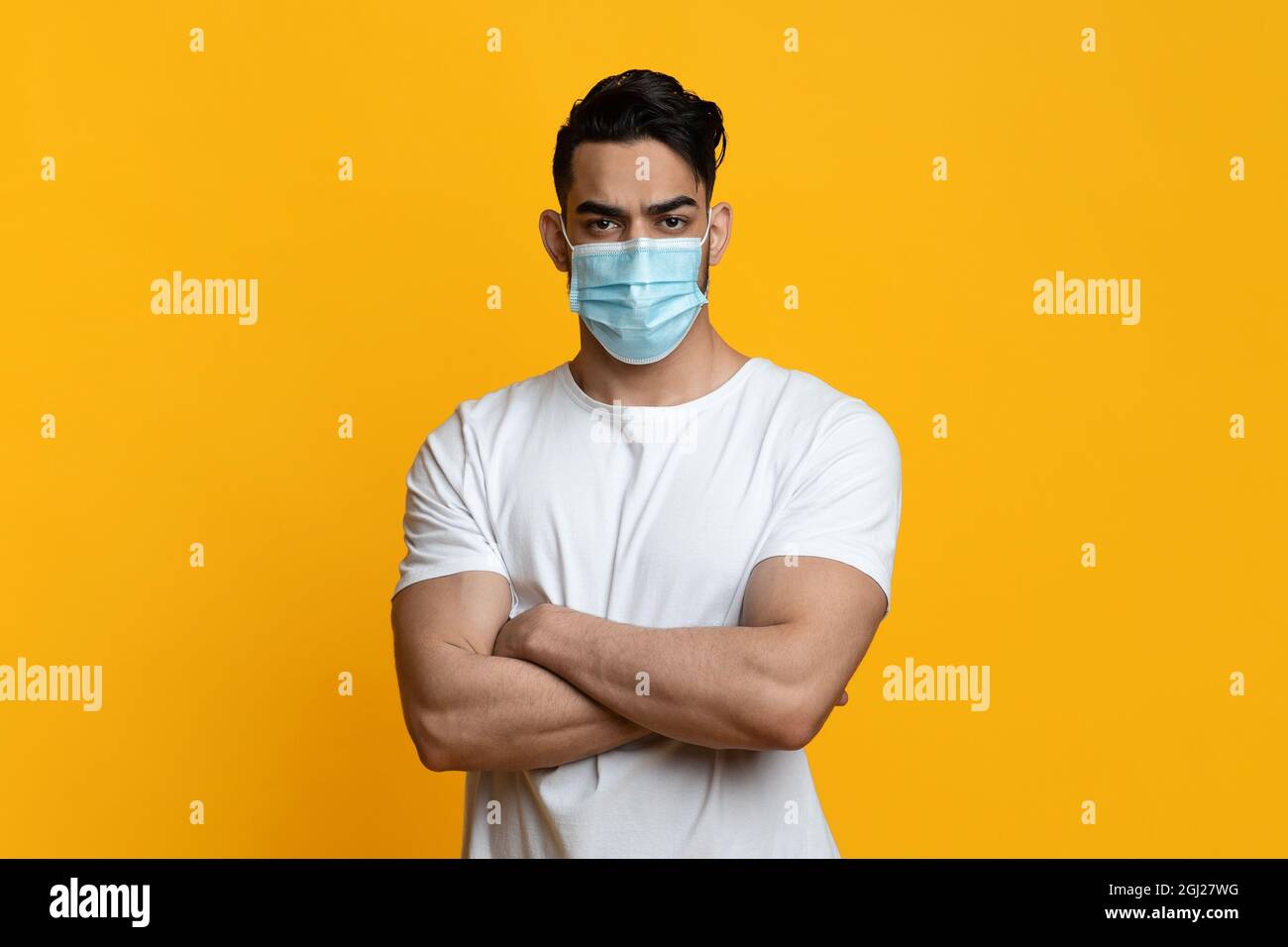 Angry arab guy with protective face mask holding arms crossed on chest ...